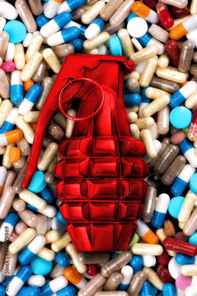 Red hand grenade on medicine capsules. Sickness and danger of abuse ...