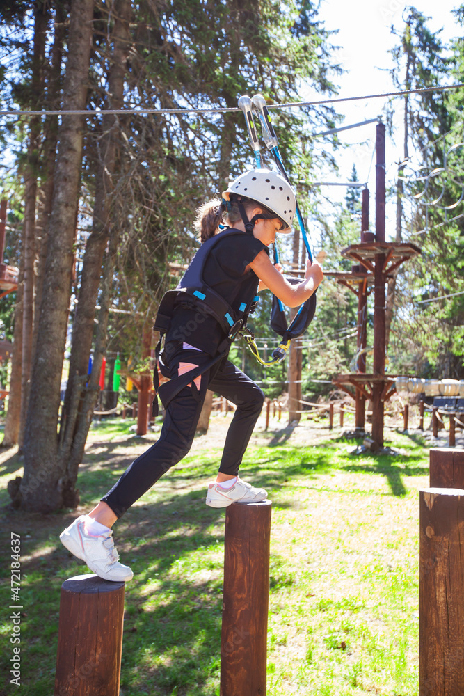 Child using safety equipment at adventure amusement park. Young girl ...