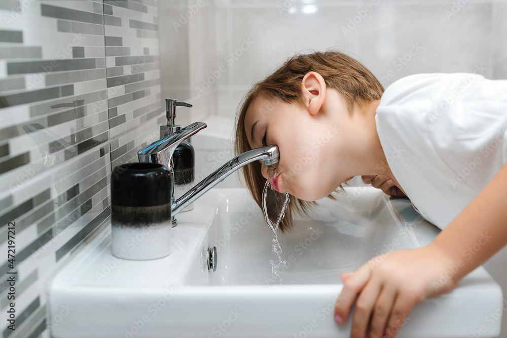 Boy washing face in the bathroom. Morning hygiene. Preteen boy is ...