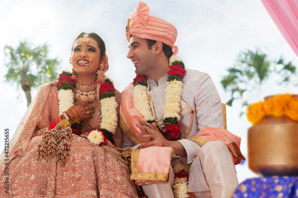 Happy Indian bride and groom sitting together at wedding mandap Stock ...