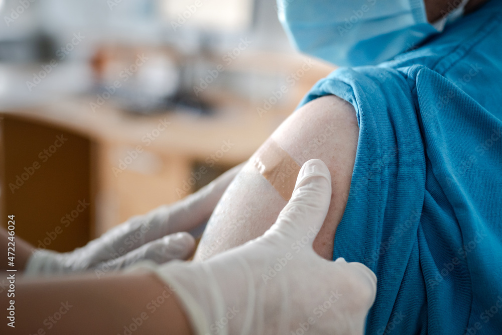 A close-up picture of a doctor putting a band-aid on a patient arm ...