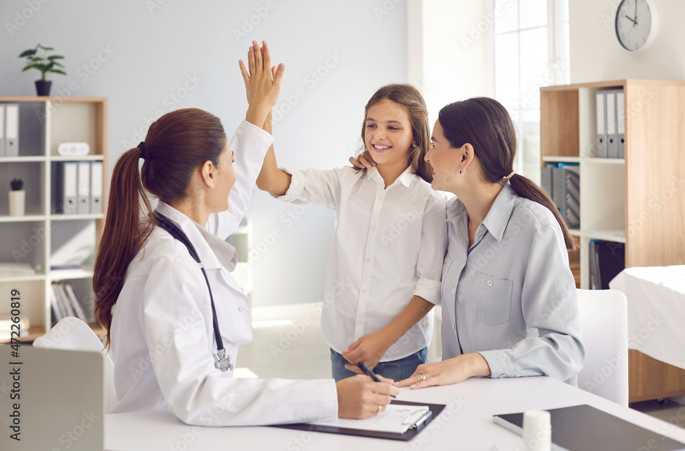 Happy little girl who visits doctor with her mother gives high five to ...
