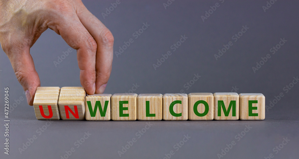 Welcome or unwelcome symbol. Businessman turns wooden cubes and changes ...