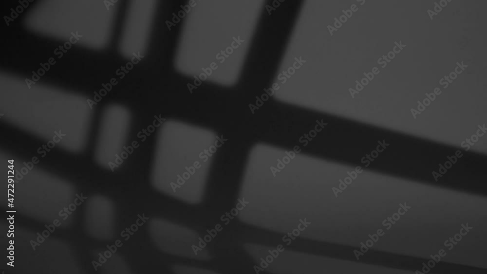 The shadow of a window moves along the surface of a gray wall at night ...