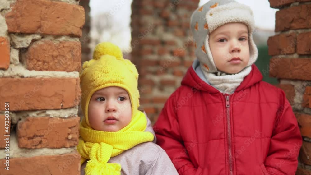 baby runing.Two little kids in grey jumpsuit yellow hat walking through ...