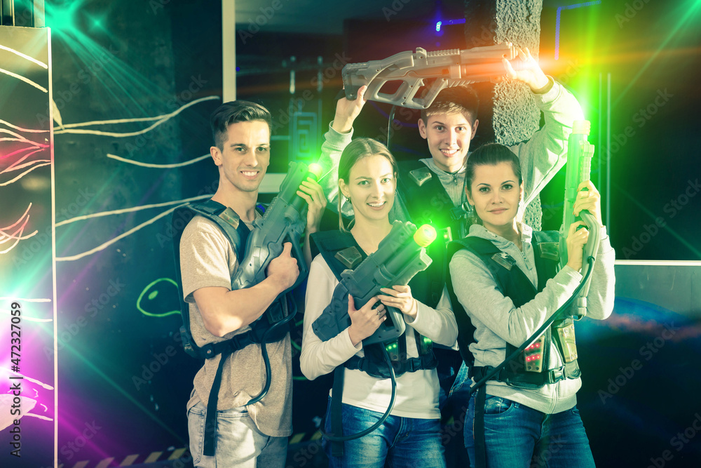 Portrait of cheerful young friends with laser guns during lasertag game ...