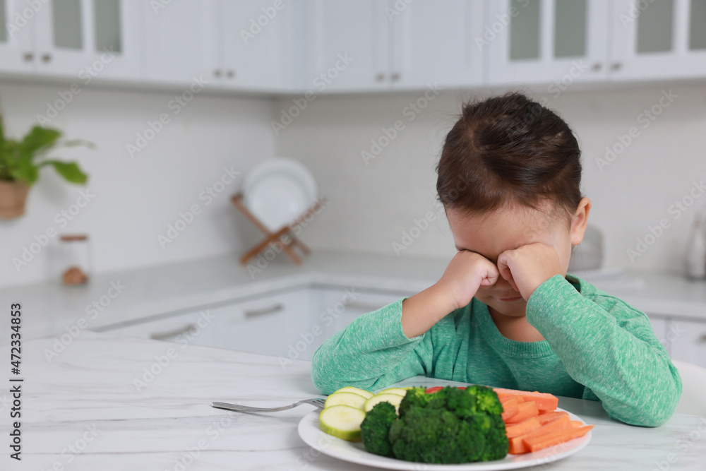Cute little girl crying and refusing to eat vegetables in kitchen ...