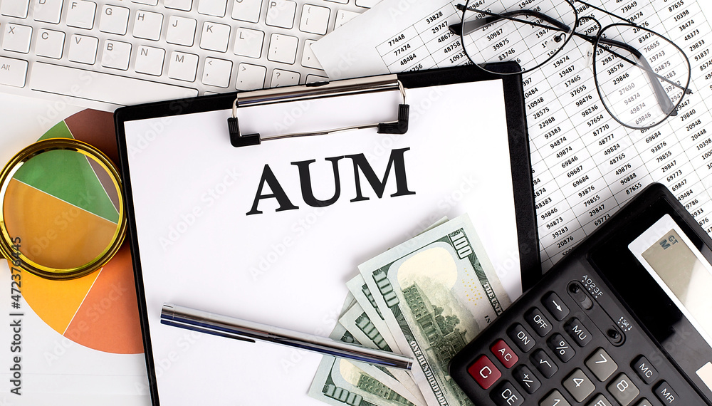 Text AUM -ASSET UNDER MANAGEMENT on Office desk table with keyboard ...