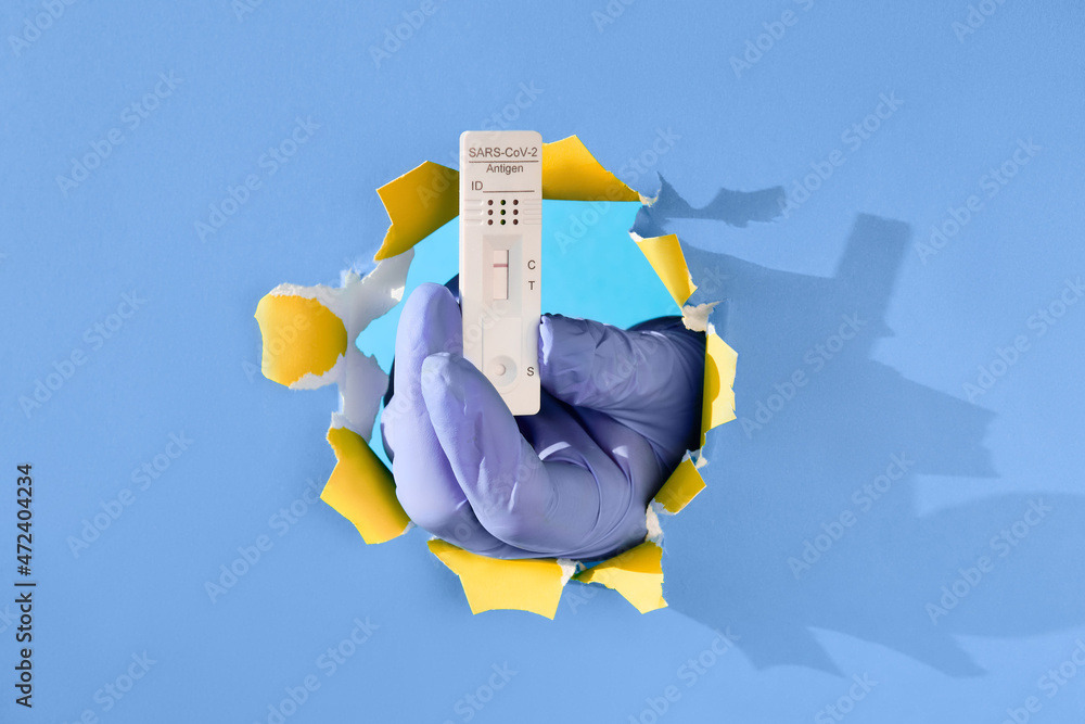Fast covid test in hand in glove through paper hole. Hand holding quick ...