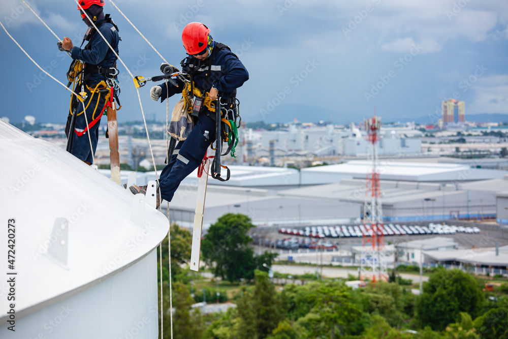Male two workers control rope down top roof tank rope access inspection ...