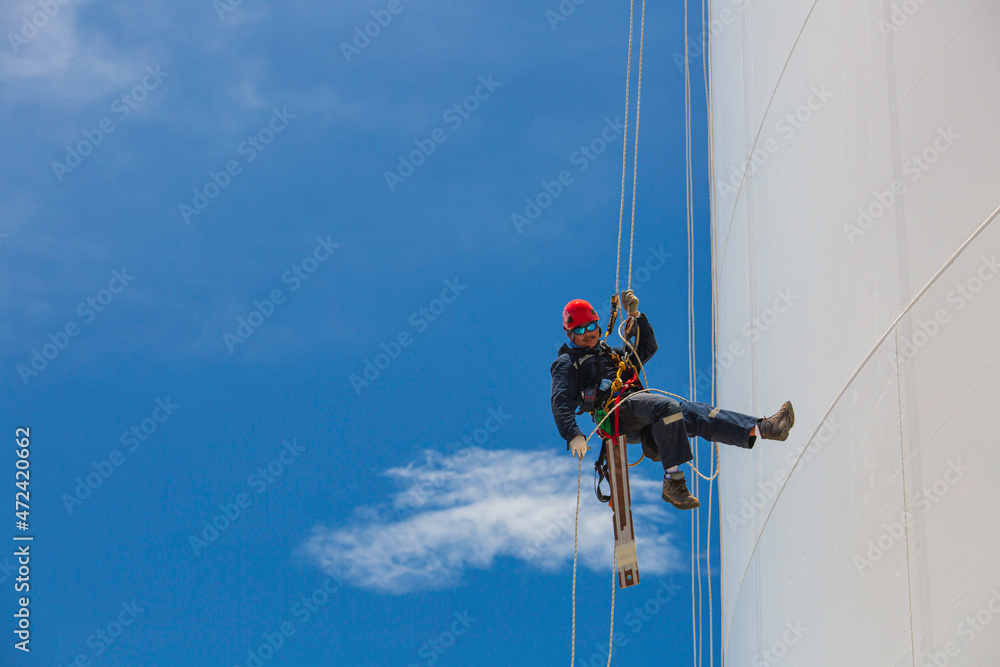 Male workers control swing rope down height tank rope access inspection ...