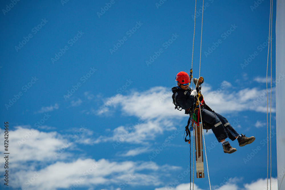 Male workers control swing rope down height tank rope access inspection ...