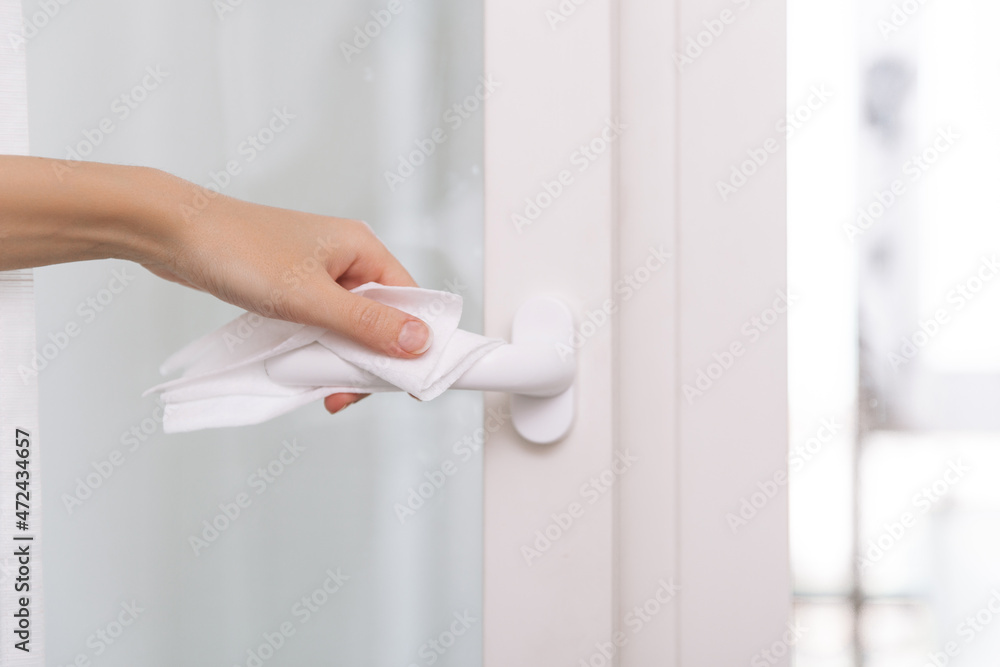 Cleaning door handles with an antiseptic wet wipe and gloves. Woman ...