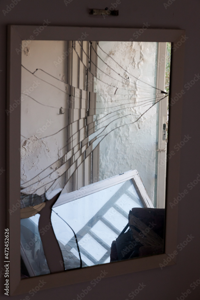 Broken glass with cracks and reflection of abandoned room. The mirror ...