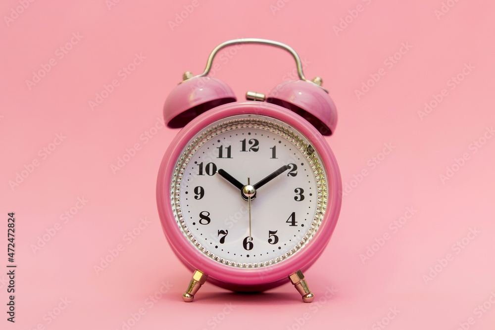 Little pink retro alarm clock on pink isolated background. It's time to ...