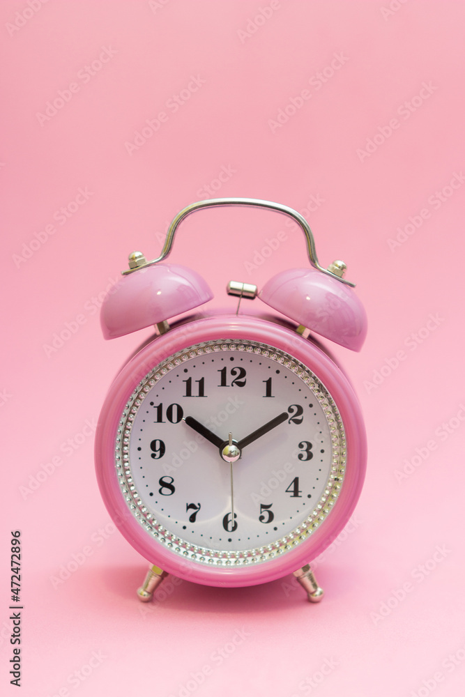 Little pink retro alarm clock on pink isolated background. It's time to ...