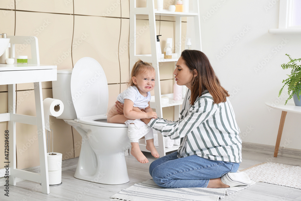 Woman teaching her baby to use toilet bowl in bathroom Stock Photo ...