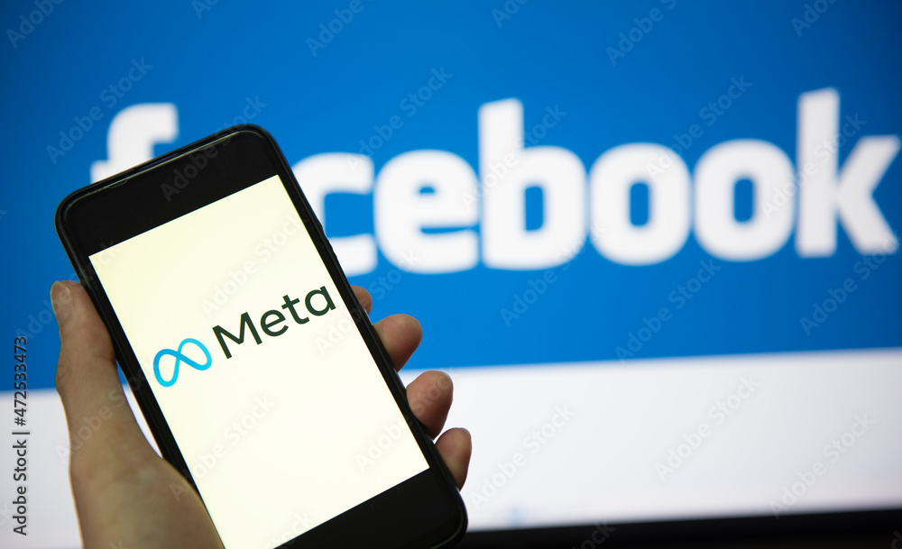 META logo on smartphone screen with hand hold and facebook logo on ...