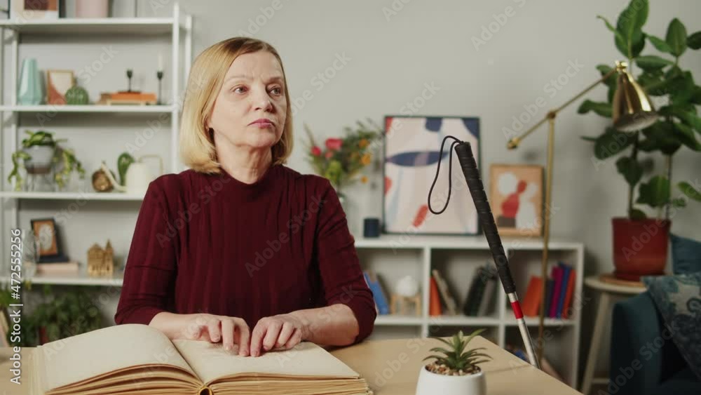 Blind woman reading braille book using fingers, sitting in living room ...