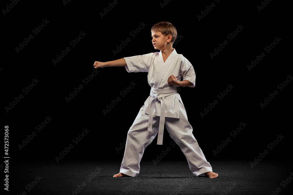 Full-length portrait of little boy, sportsman standing in front stance ...