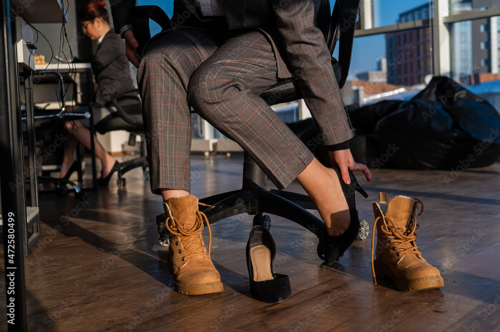 Business woman changes shoes with high heels on boots in the office ...