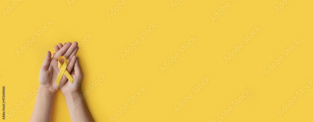 International Childhood Cancer Day. Child hands holding yellow gold ...