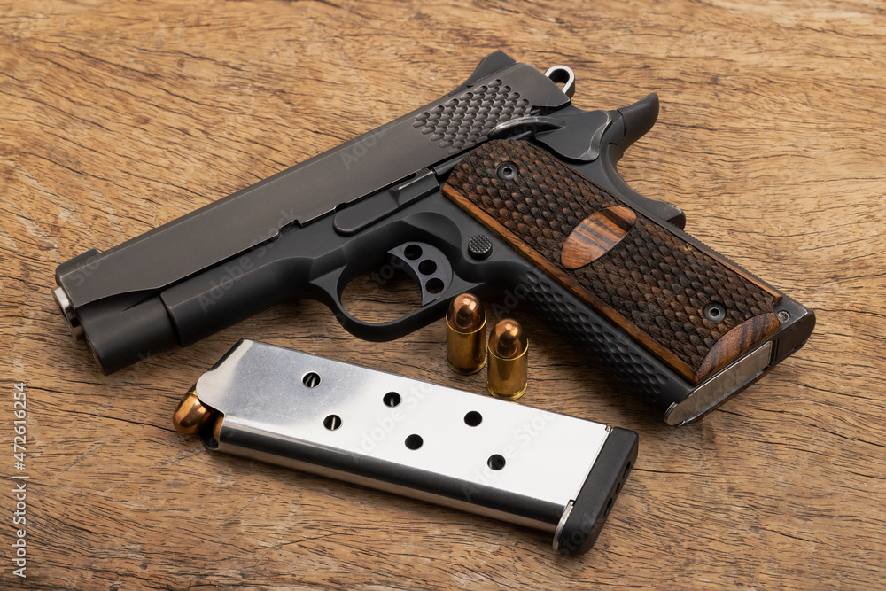 .45 Automatic pistol hand gun and bullet magazine on wooden background ...