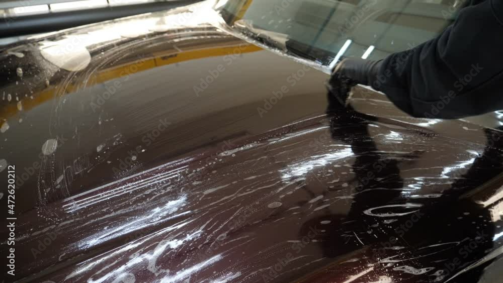 Close up to PPF installation process on a front headlight and hood. PPF ...