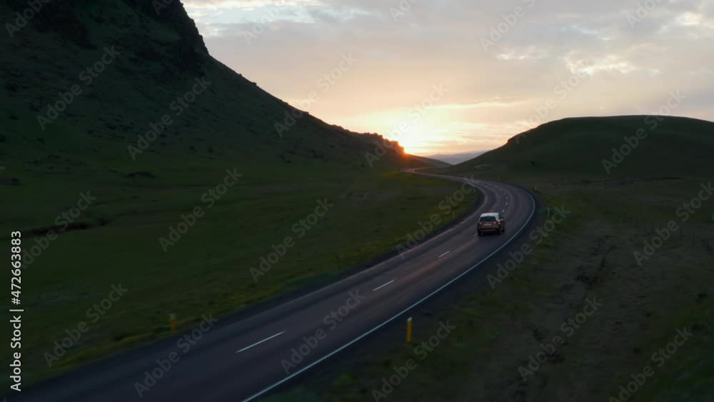 Drone view of highway car peacefully driving in golden hour in evening ...