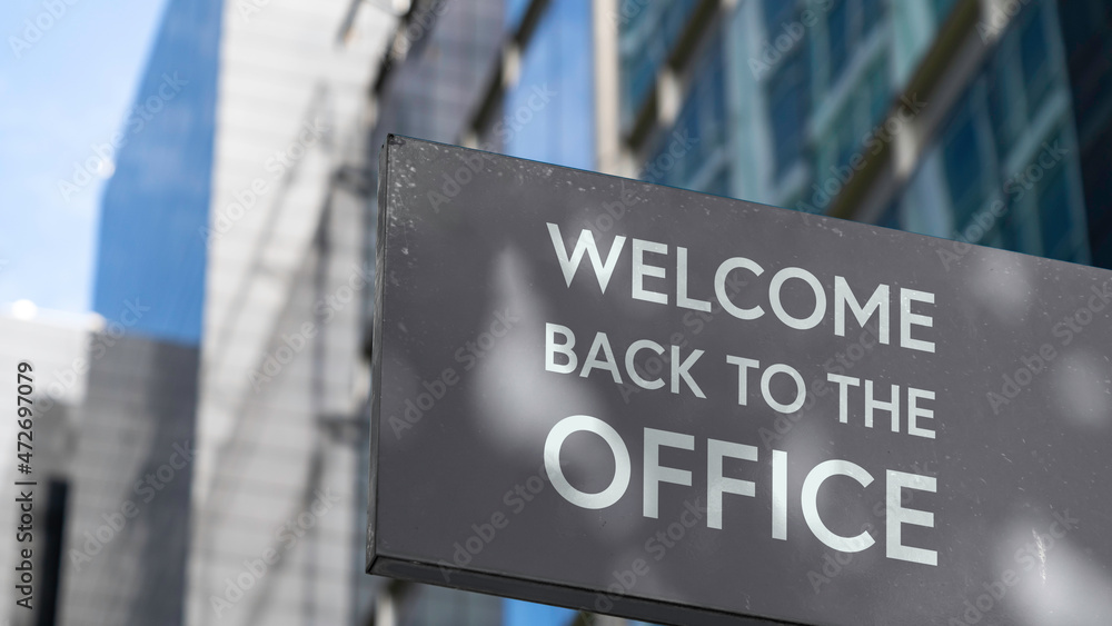 Welcome back to the office on a city-center sign in front of a modern ...