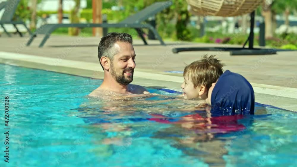 A young woman wearing a hijab swimsuit is swimming in the pool with her ...