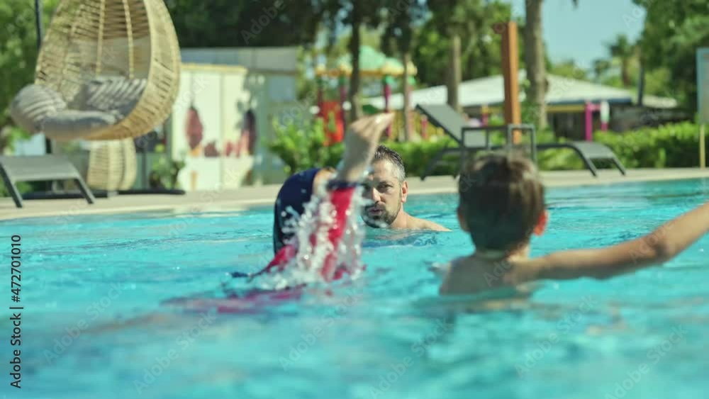 A young woman wearing a hijab swimsuit is swimming in the pool with her ...