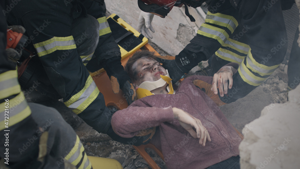 From above men in uniform saving injured teenager from rubble during ...