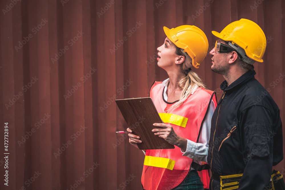 Industrial worker works with co-worker at overseas shipping container ...