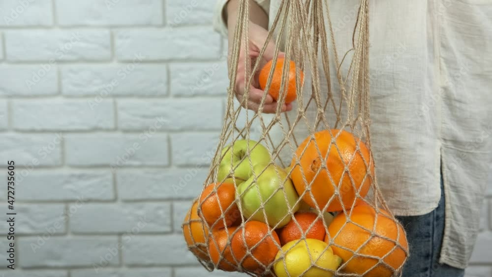 Mesh with grocery. A healthy woman hold a mesh bag with ripe organic ...