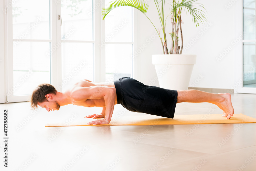 Male doing low push ups while practicing yoga in light room Stock Photo ...