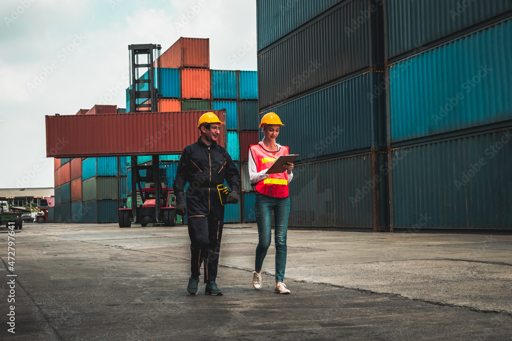 Industrial worker works with co-worker at overseas shipping container ...