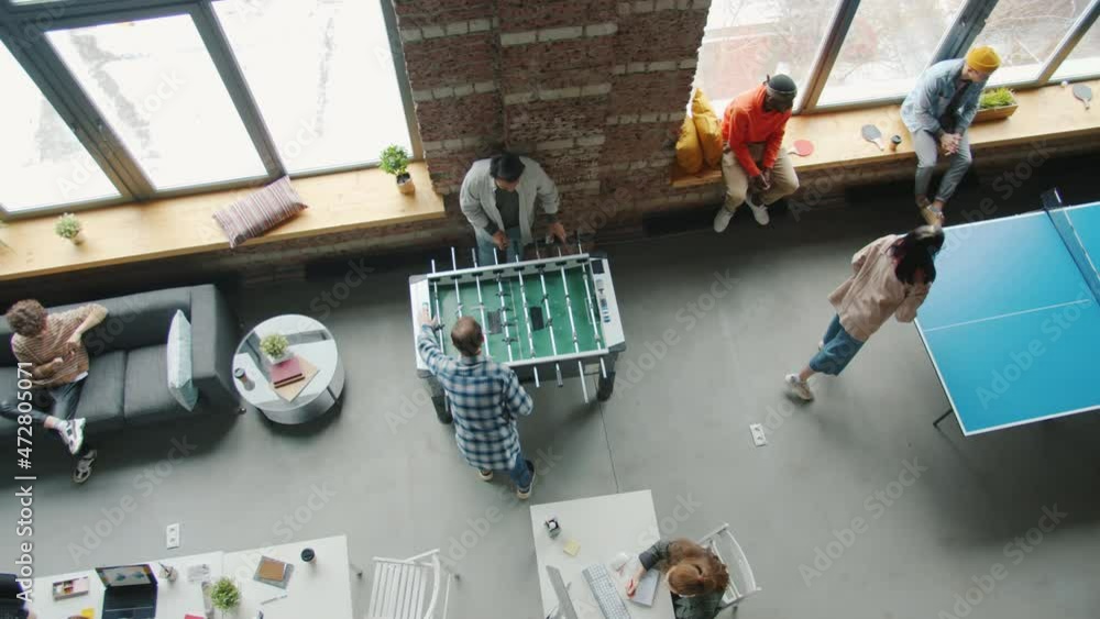 Top view of colleagues playing foosball and ping pong games indoors in ...