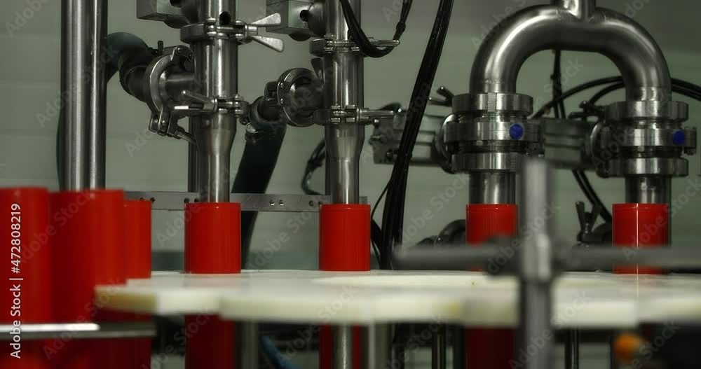 Machine oil production plant. Red plastic bottles move along a conveyor ...