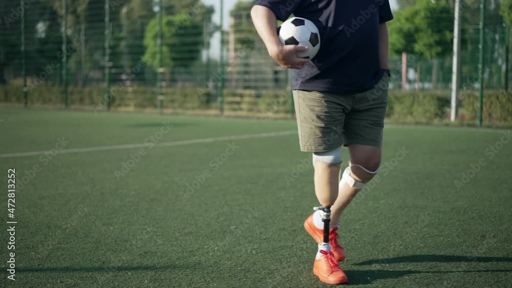 Unrecognizable man with artificial limbs and soccer ball walking in ...