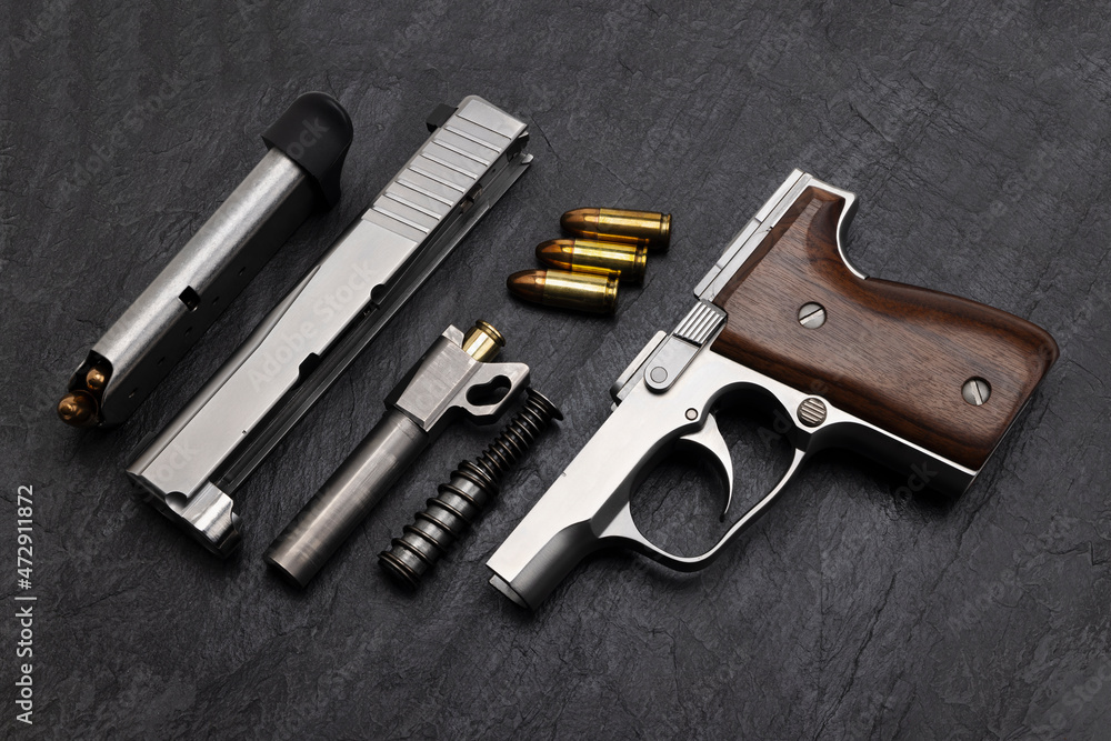 Parts of semi automatic pistol handgun with bullets on black slate ...