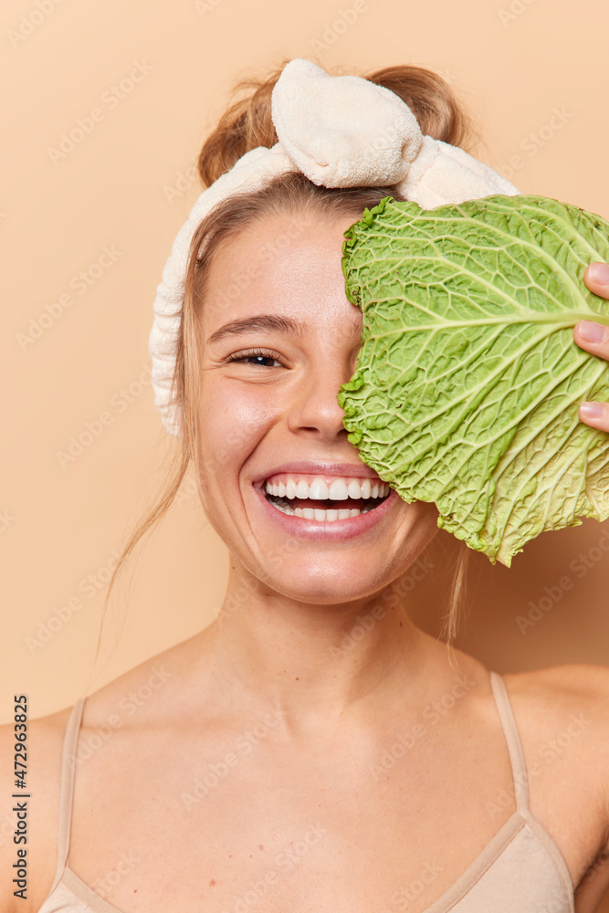 Positive woman with healthy glowing skin uses natural cosmetics covers ...