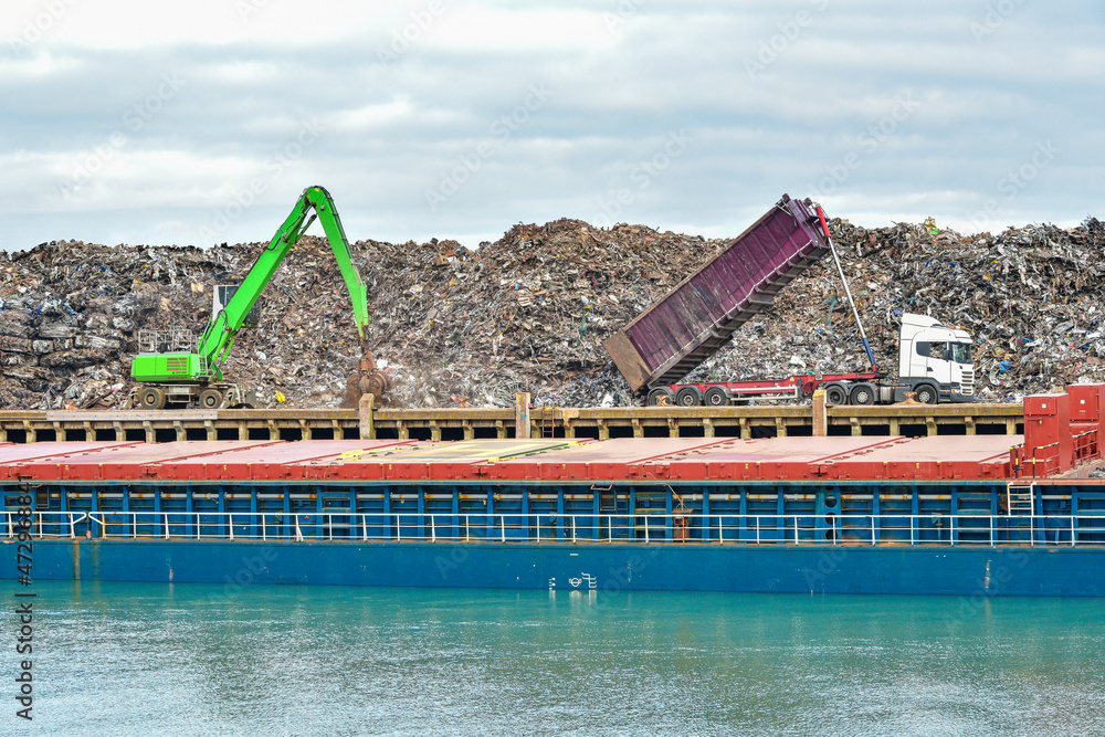 Machine operated grabbing arm, loading scrap metal onto a ship in the ...