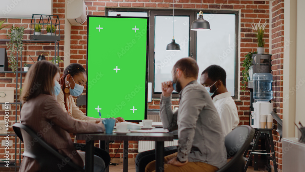 Poeple with face mask looking at monitor with green screen in business ...