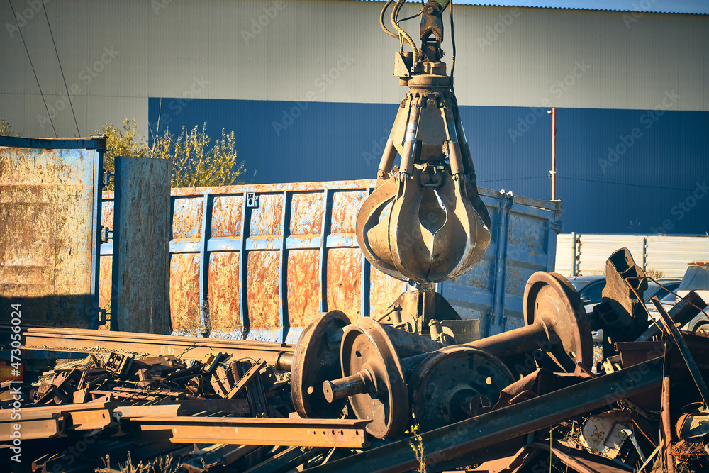 Magnet crane unloads scrap metal from truck. Hand of grabber excavator ...