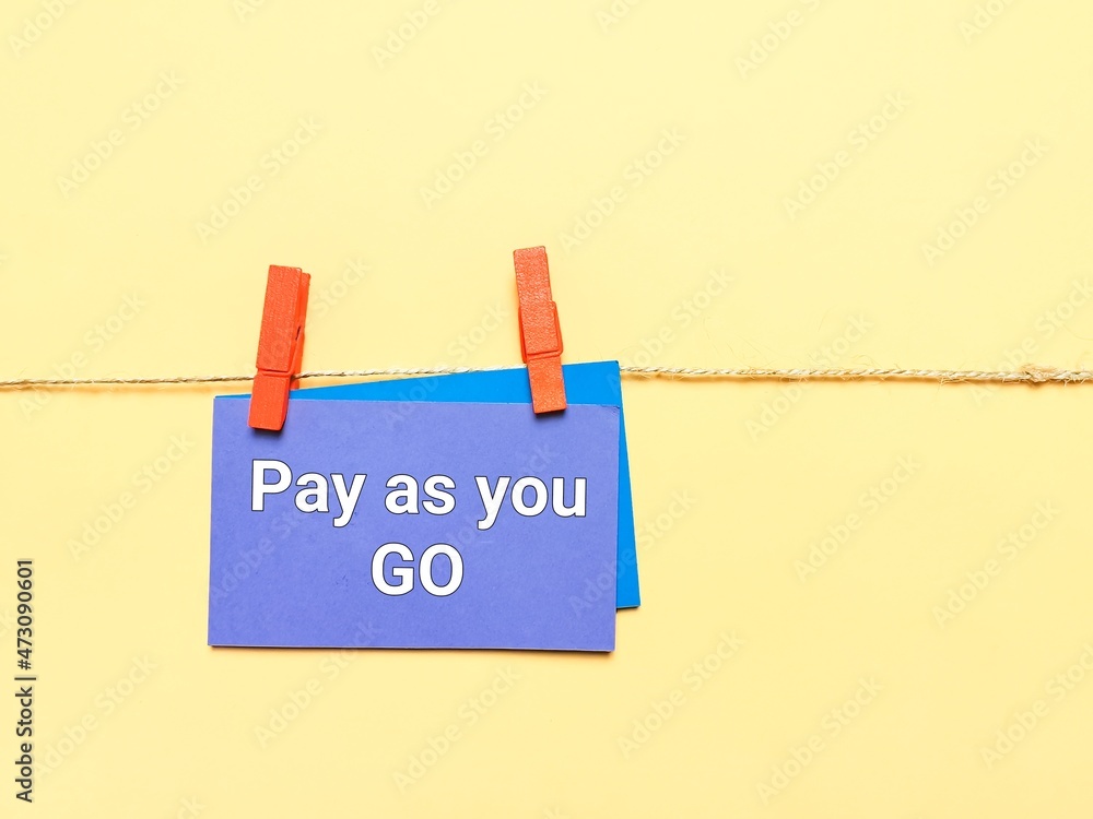 Purple paper card written pay as you go hanging on clothes line against ...