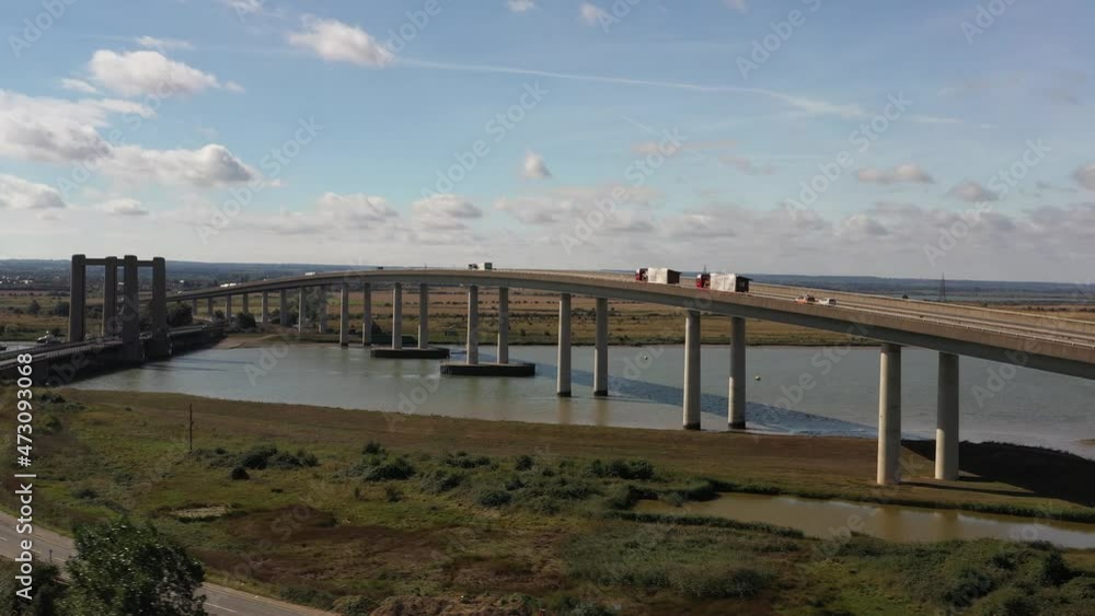tall highway bridge spanning water surface. Concrete columns supporting ...