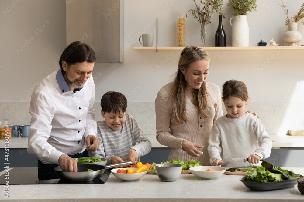 Happy young couple parents enjoying cooking with cheerful little kids ...