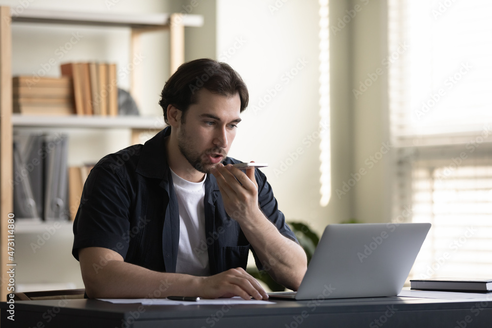 Serious millennial business man recording audio message on smartphone ...