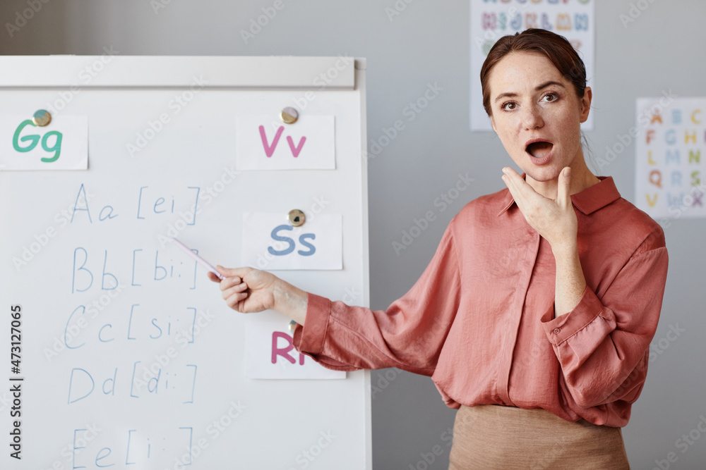 Portrait of young English teacher pointing at whiteboard with English ...